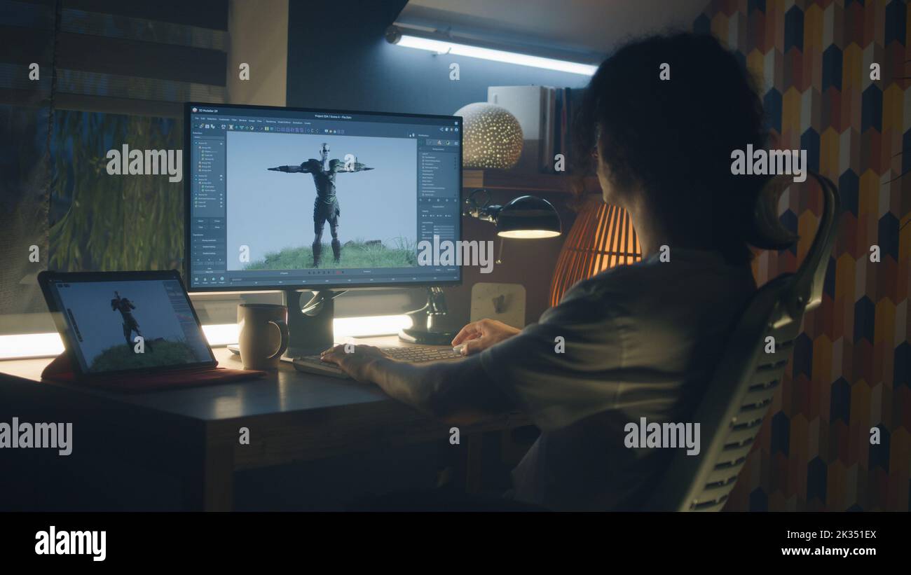 Male 3D designer sitting at the table at home and making animation for video game character ...