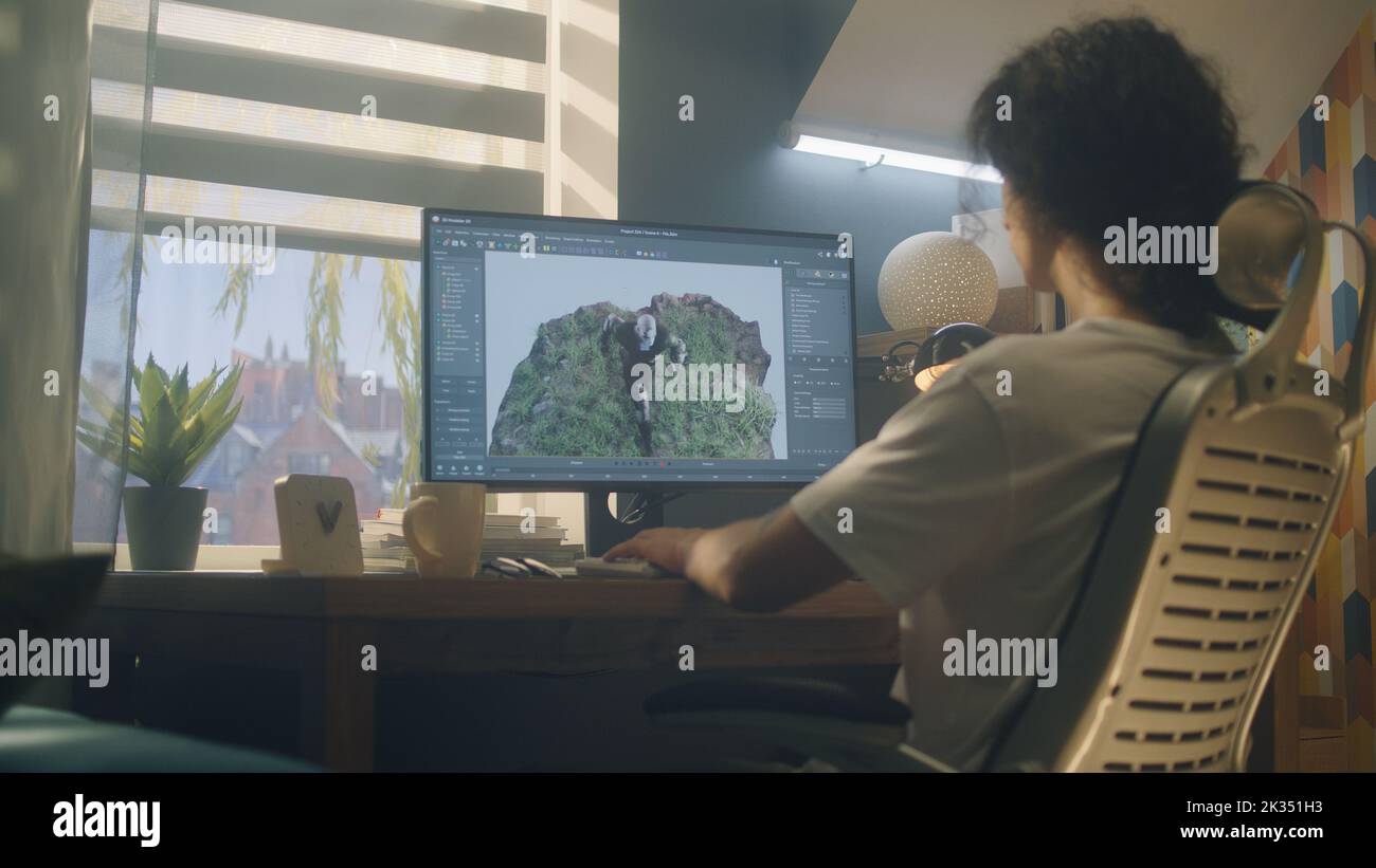 Male 3D designer sitting at the table at home and making animation for ...