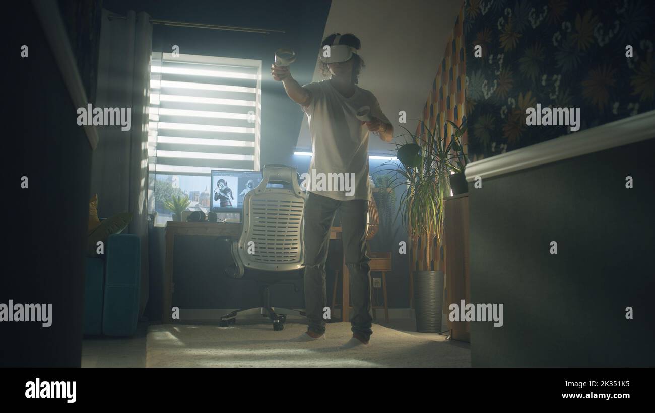 Guy moving while playing video game at home using VR headset and ...