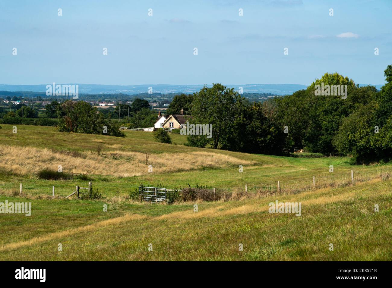 The Gloucestershire village with green fields, fence and town in ...