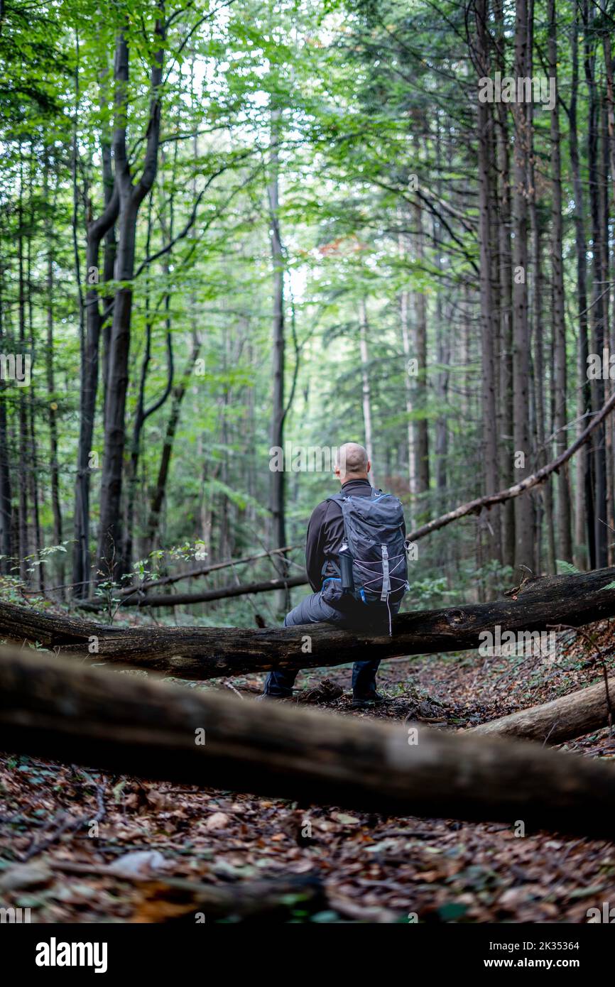 A mountaineer (hiker) (not recognizable) with a backpack is sitting on ...