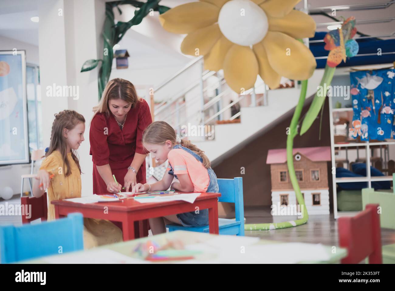 Creative kids during an art class in a daycare center or elementary school classroom drawing ...