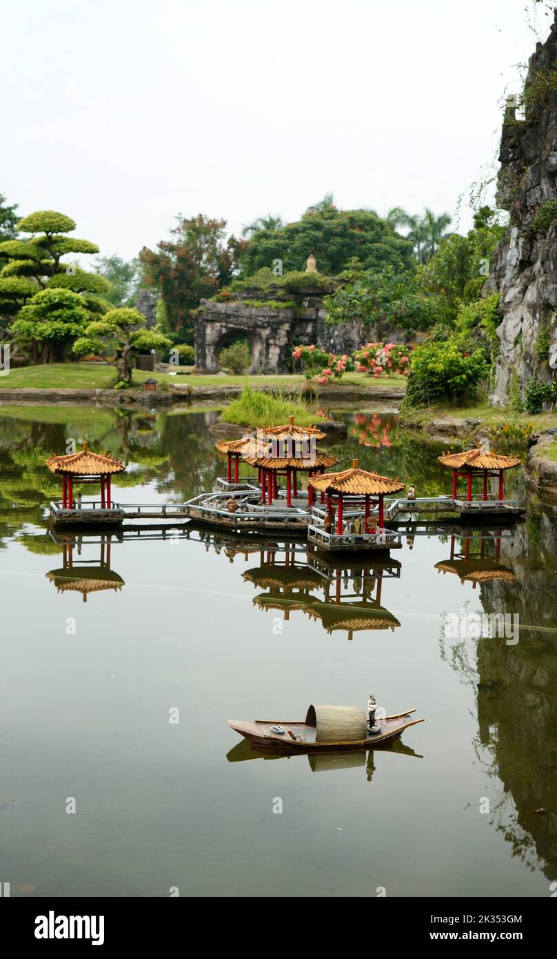 A vertical shot of a garden with a chinese style garden house on a lake ...