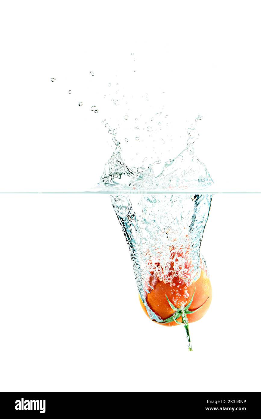 A Red tomato falling into water splash on a white background Stock ...
