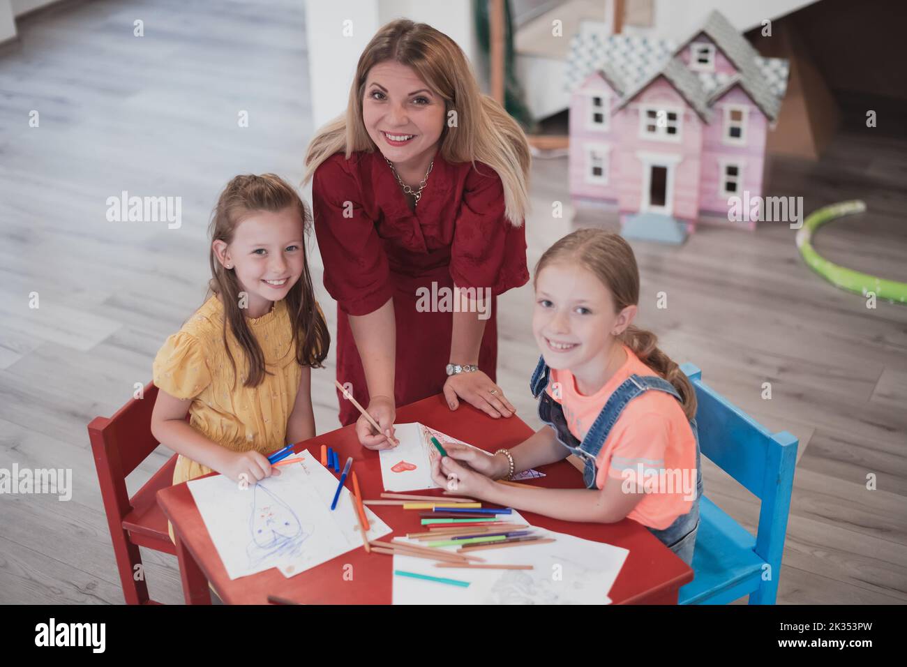 Creative kids during an art class in a daycare center or elementary school classroom drawing ...