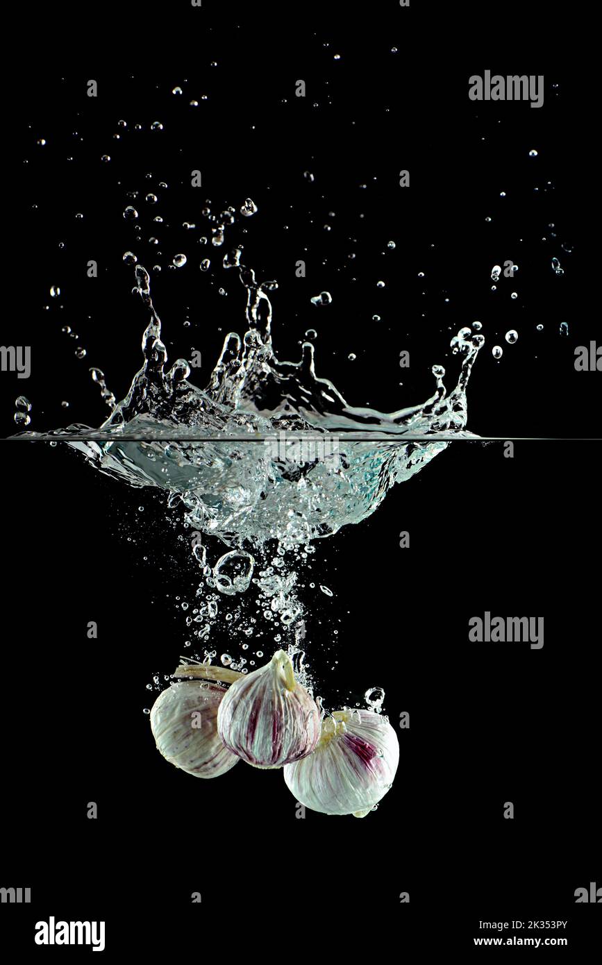 A Garlic falling into water splash on a black background Stock Photo ...
