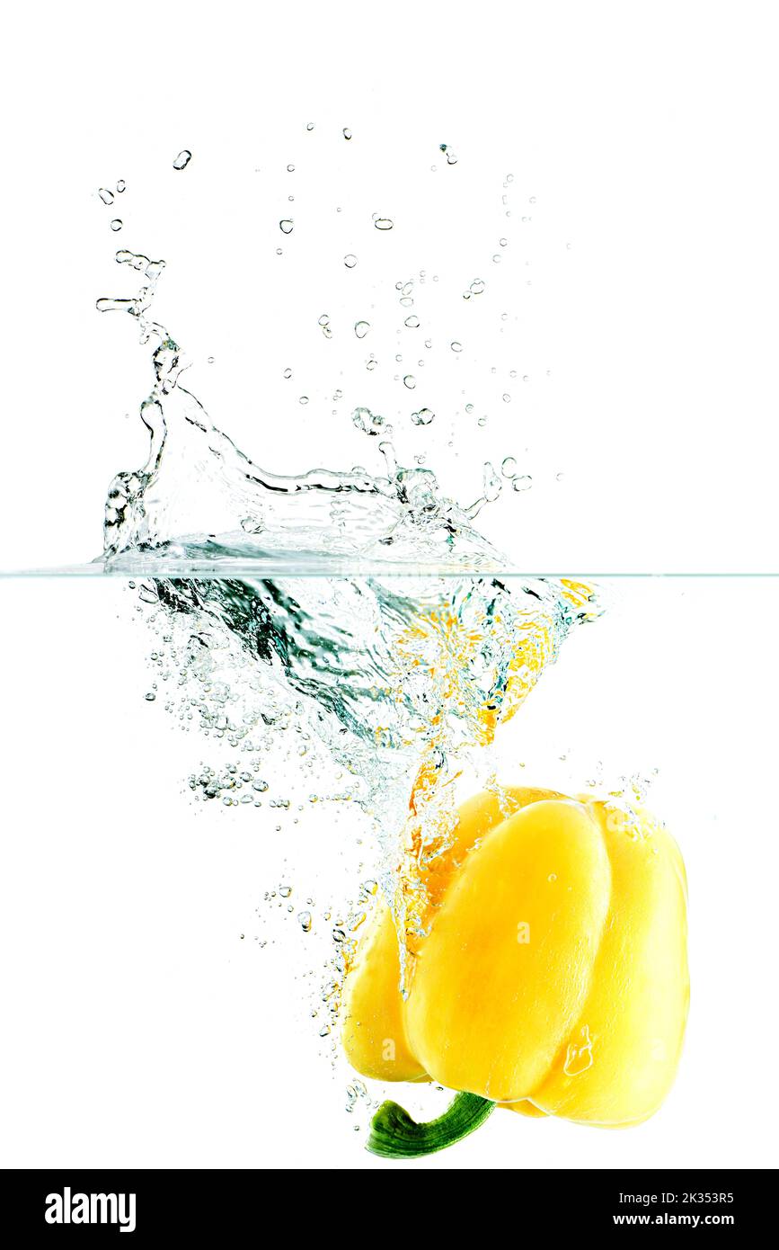 A Yellow bell pepper falling into water splash on a white background ...
