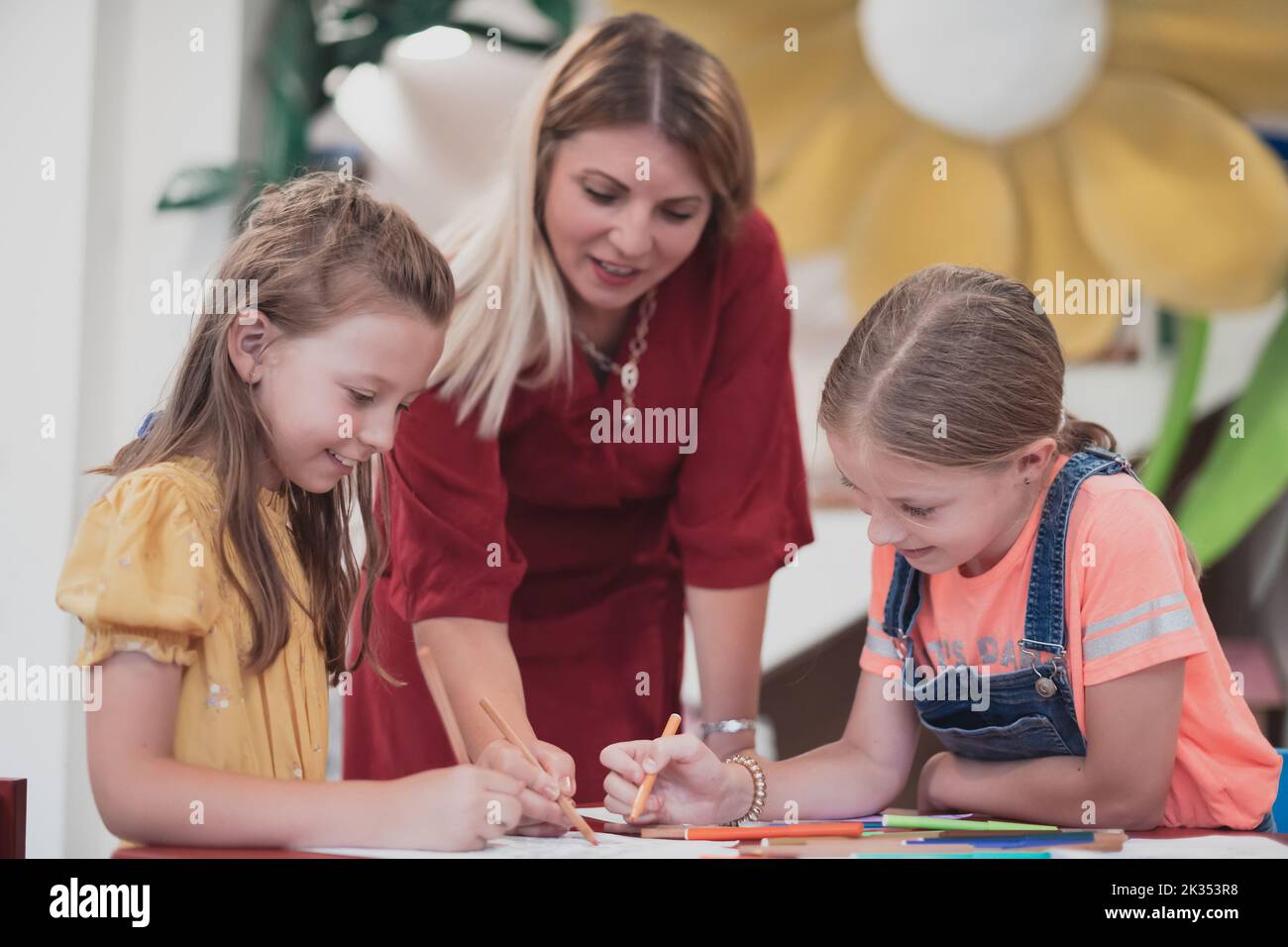Creative kids during an art class in a daycare center or elementary school classroom drawing ...