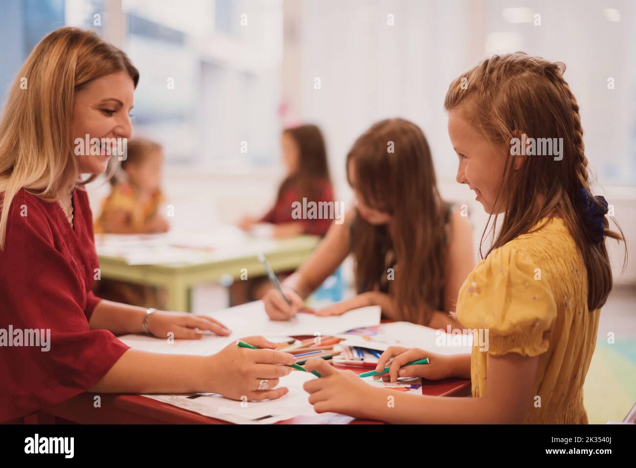 Creative kids during an art class in a daycare center or elementary school classroom drawing ...