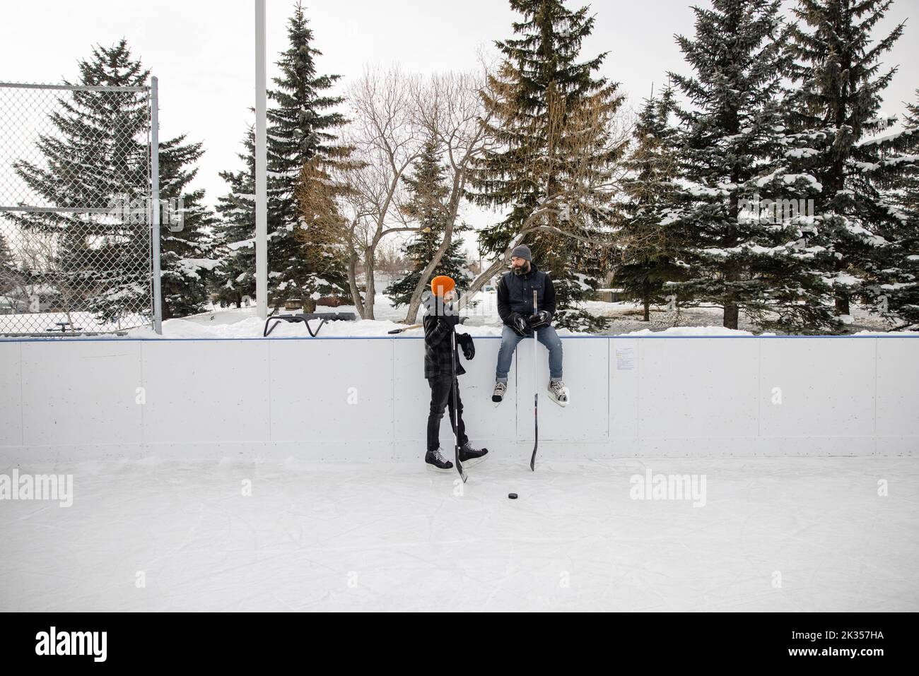 Male friends taking a break from ice hockey at winter park ice rink ...