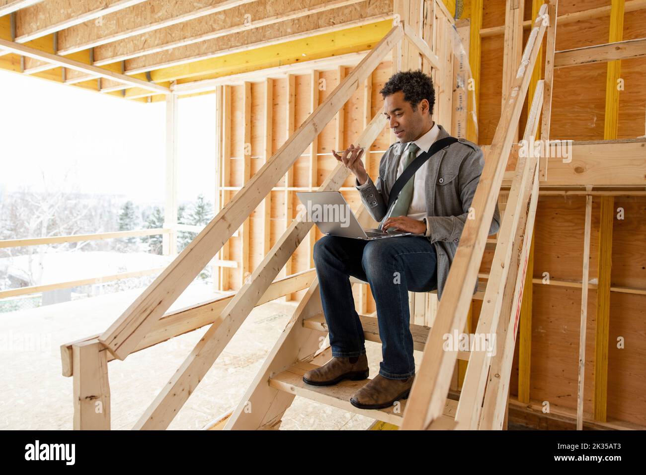 Male architect using smart phone and laptop at home construction site ...