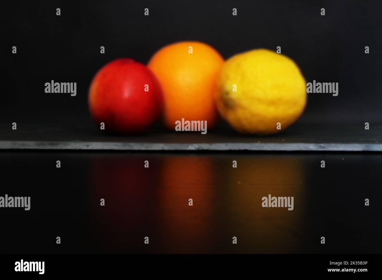 an out of focus arrangement of bright fruits on black surface Stock ...