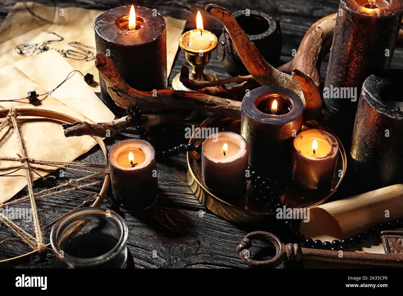 Burning candles and magic attributes for ritual on dark wooden wizard ...