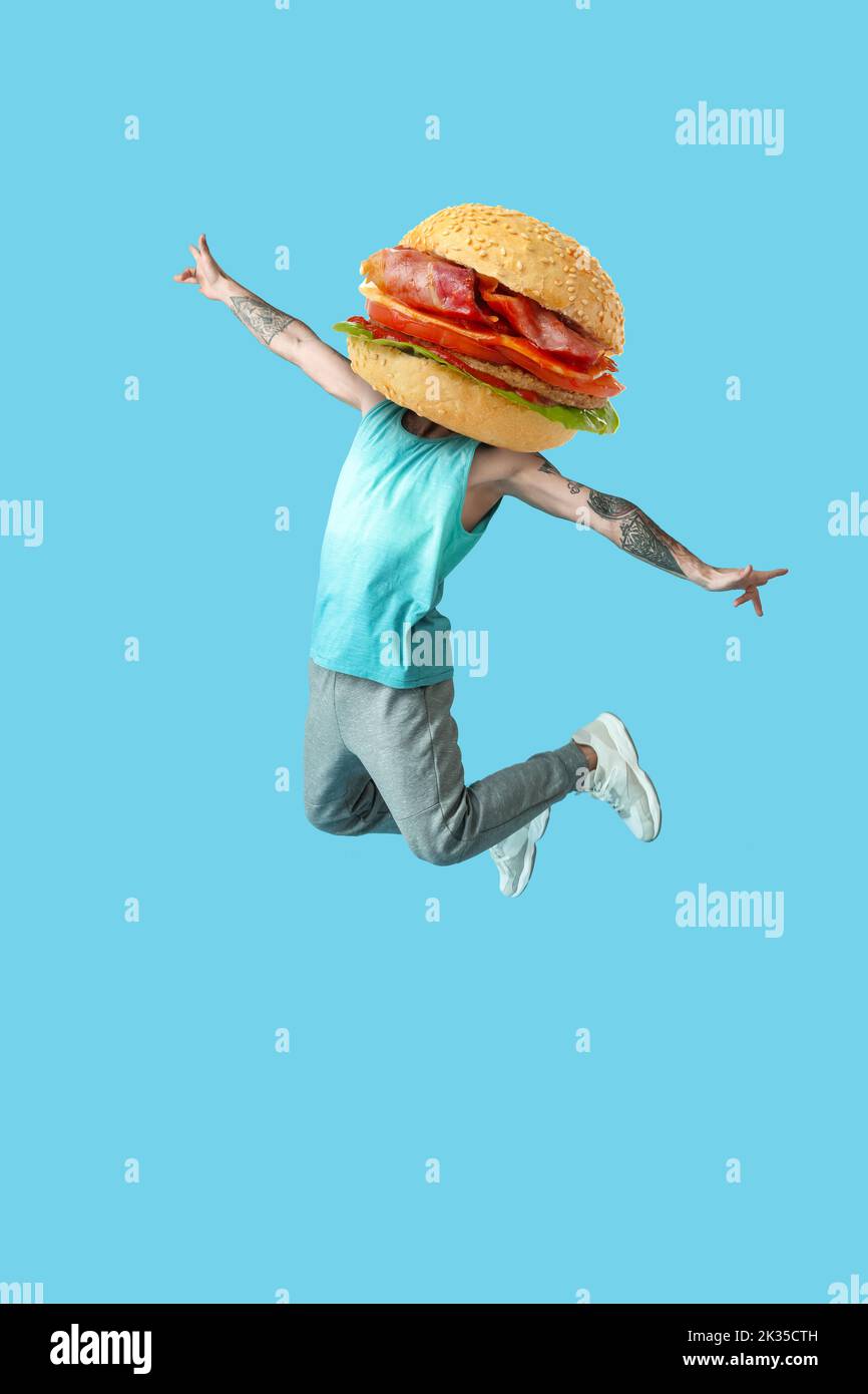 Jumping tattooed man with tasty burger instead of his head on light ...