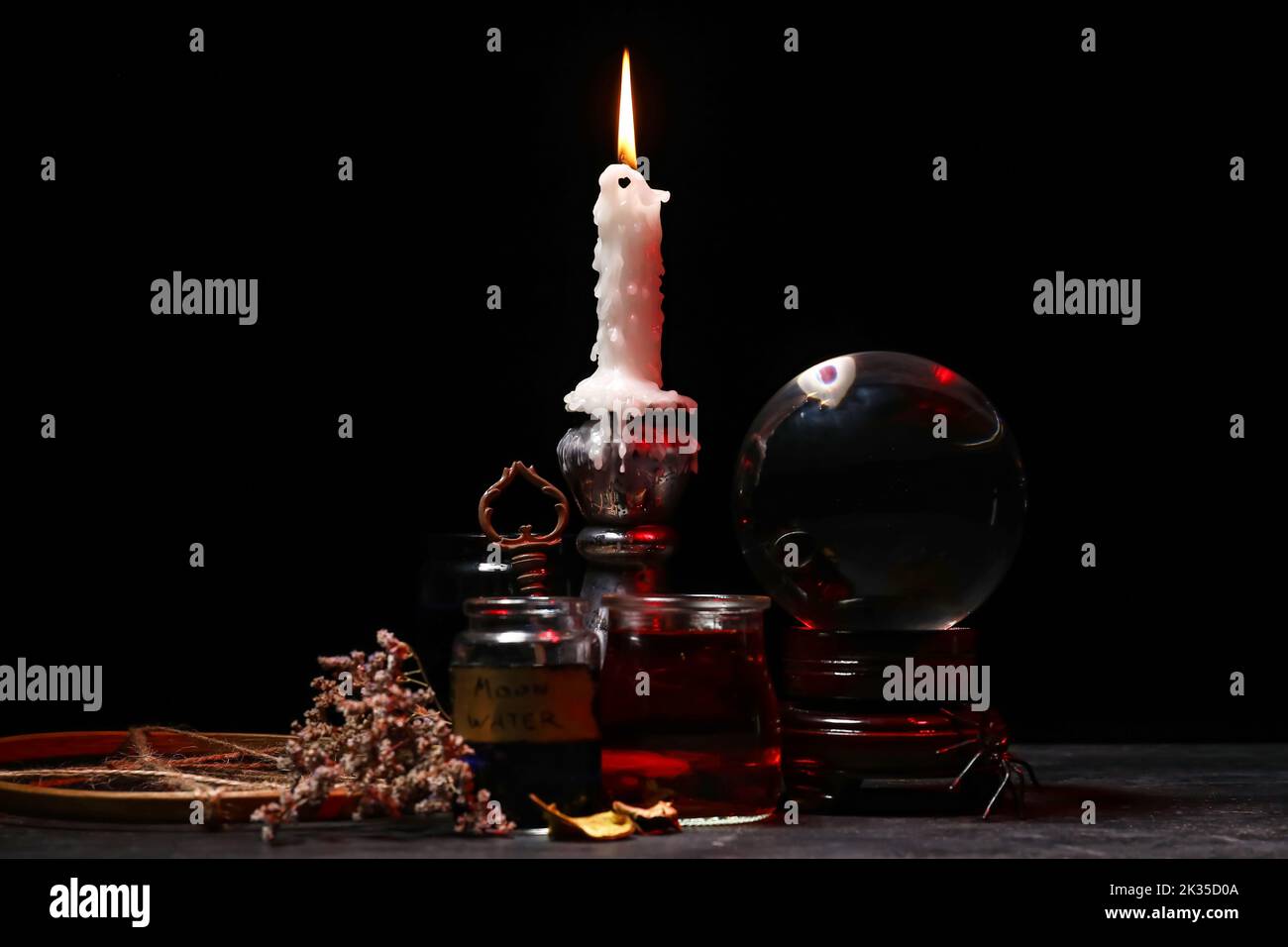 Burning candle, jars with potion and crystal ball on dark background ...