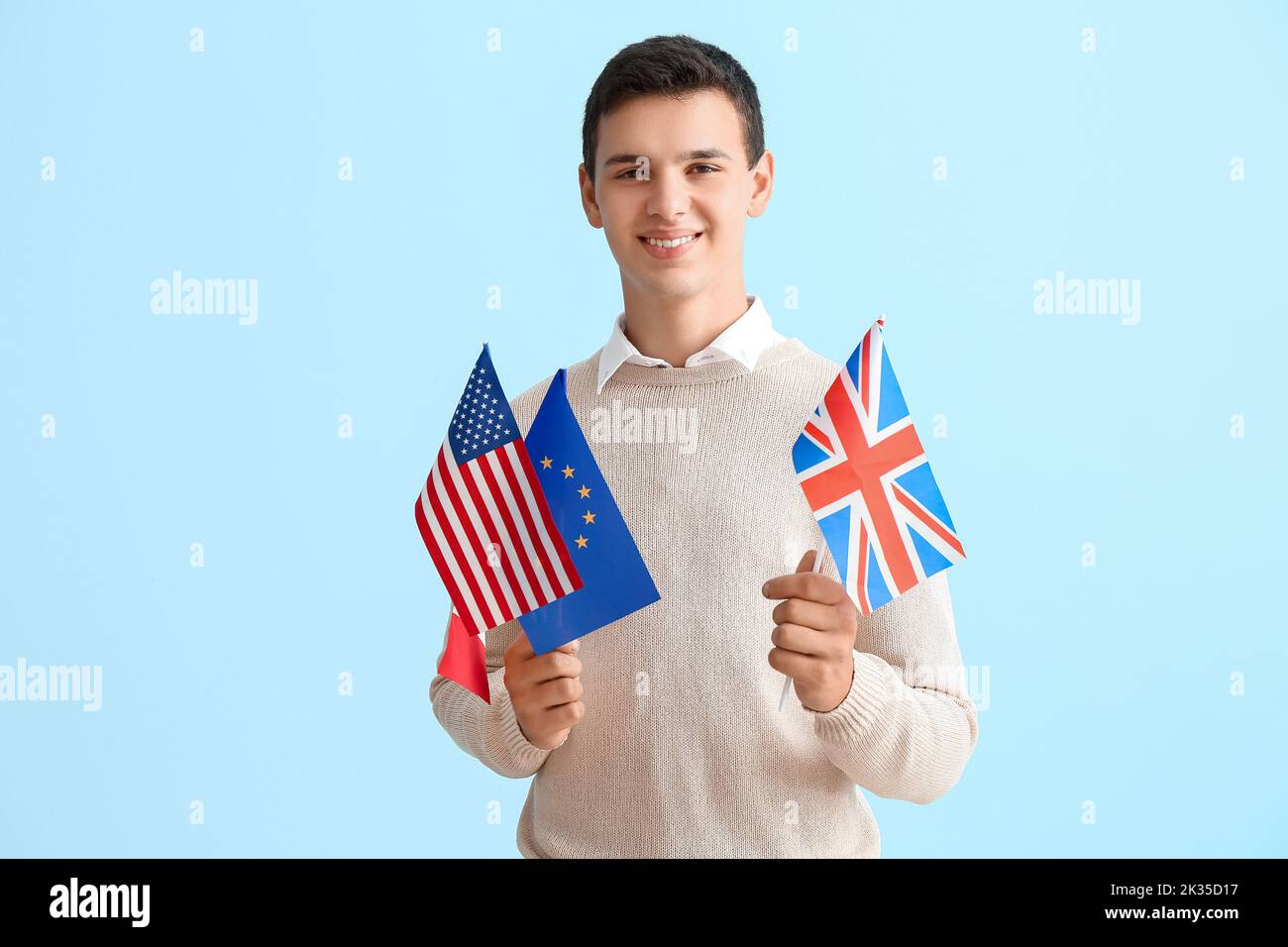 Teenage boy with flags of UK, USA and European Union on blue background ...