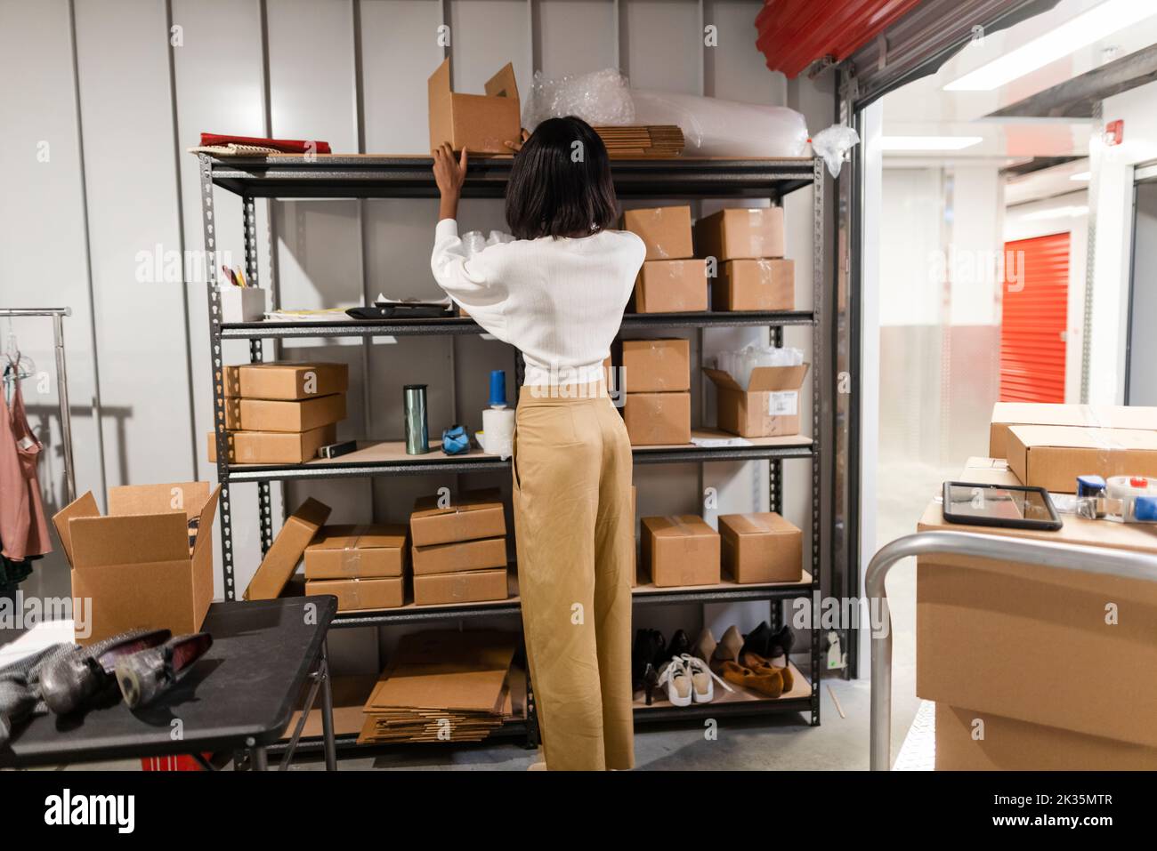 Female consignment worker with boxes in storage facility locker Stock ...