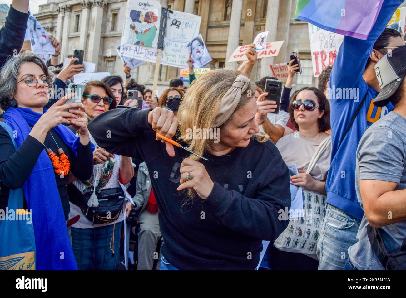 London, UK. 24th Sep, 2022. A protester cuts off a lock of her hair ...
