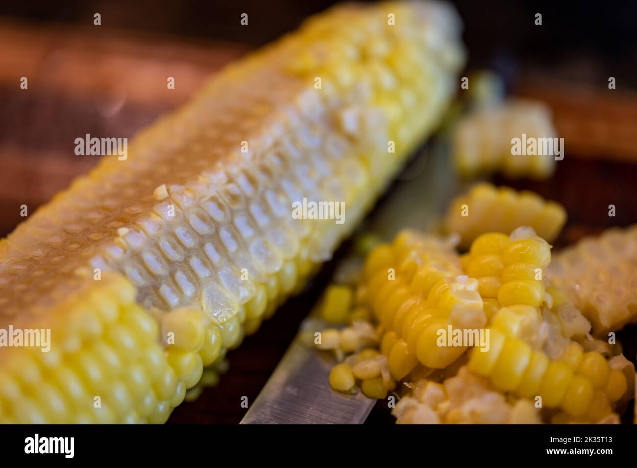 Using a knife to remove kernels from the cob of an ear of sweet corn Stock Photo - Alamy