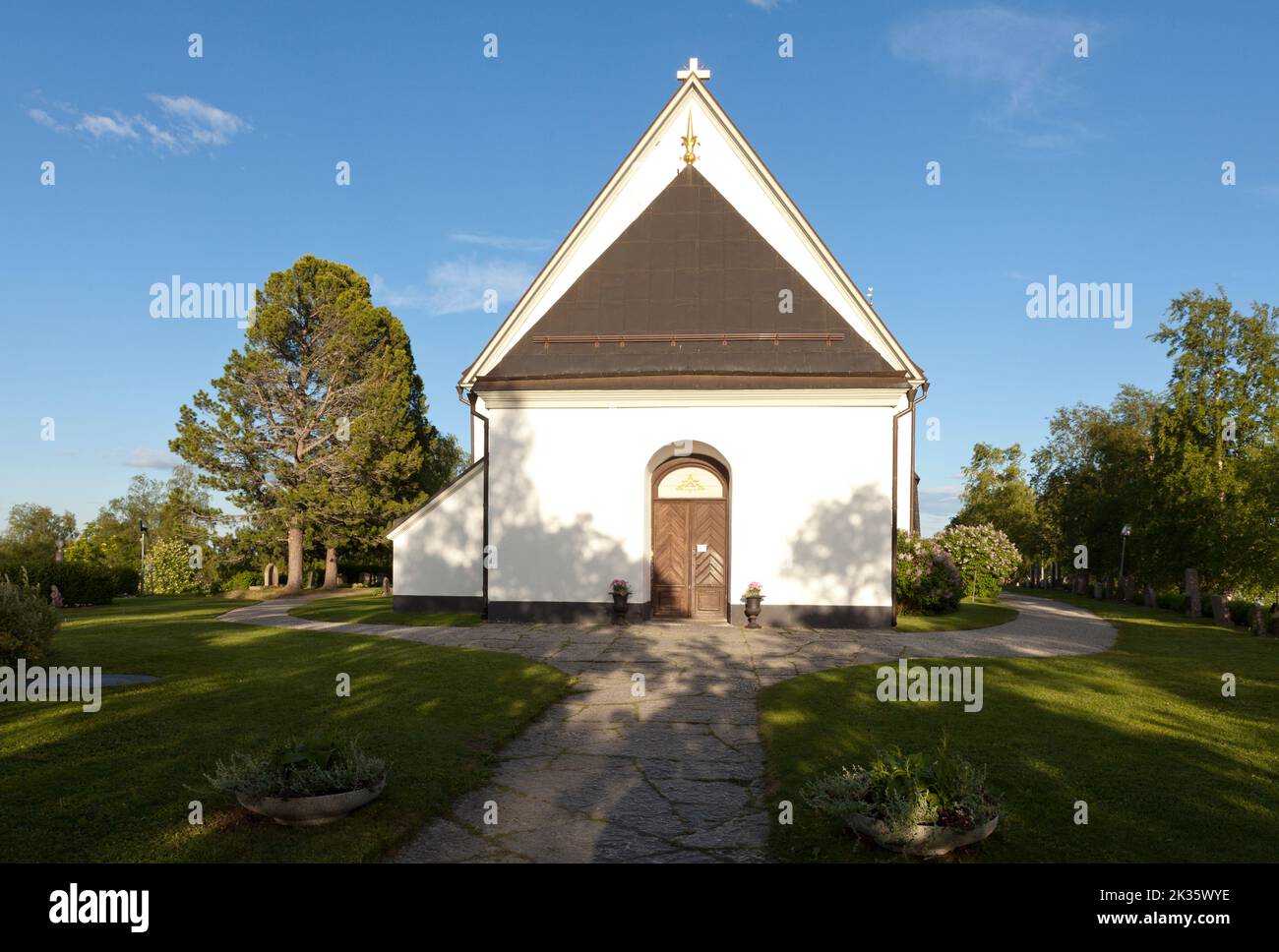 Frösö Church in evening lit, entry. Walkway and lawn in shadow this ...