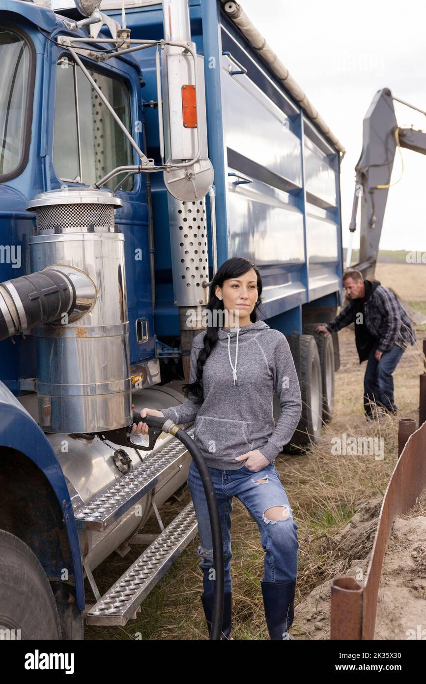 Confident female farmer filling semi truck gas tank on farm Stock Photo ...