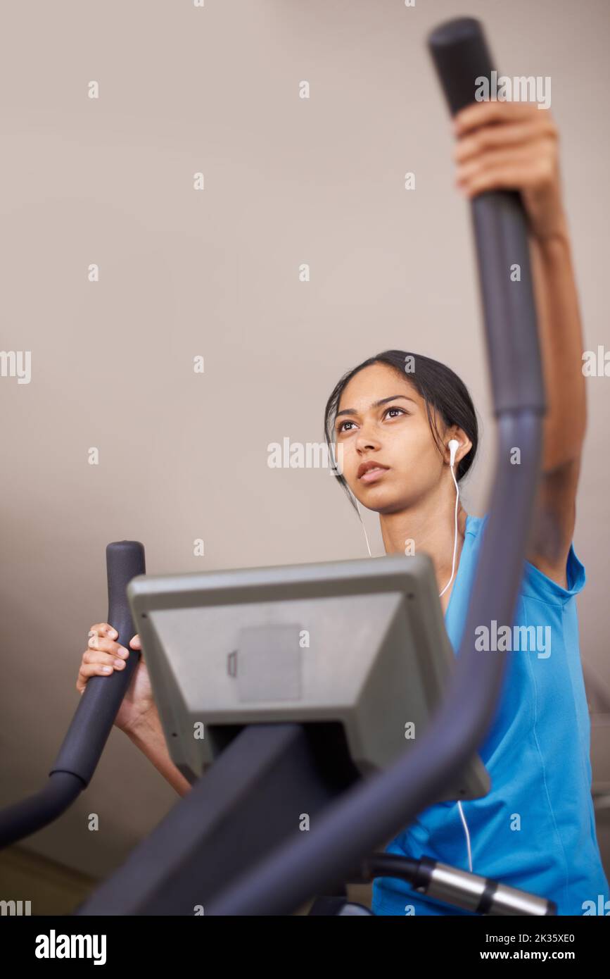 Music helps her focus. a young woman working out in the gym on a ...