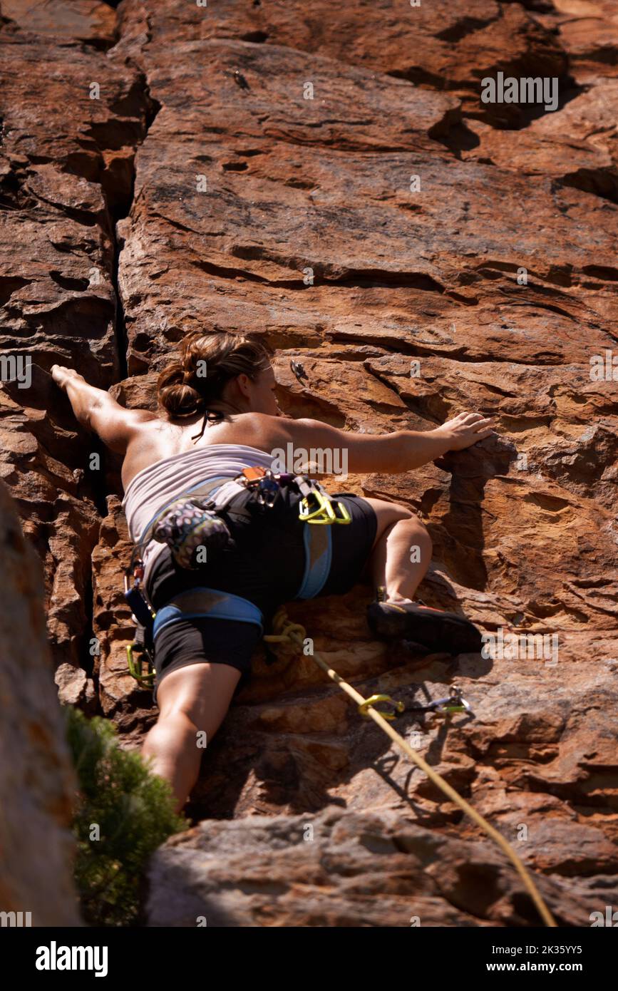 Scaling the rock face like a pro. a female rock climber doing a lead ...