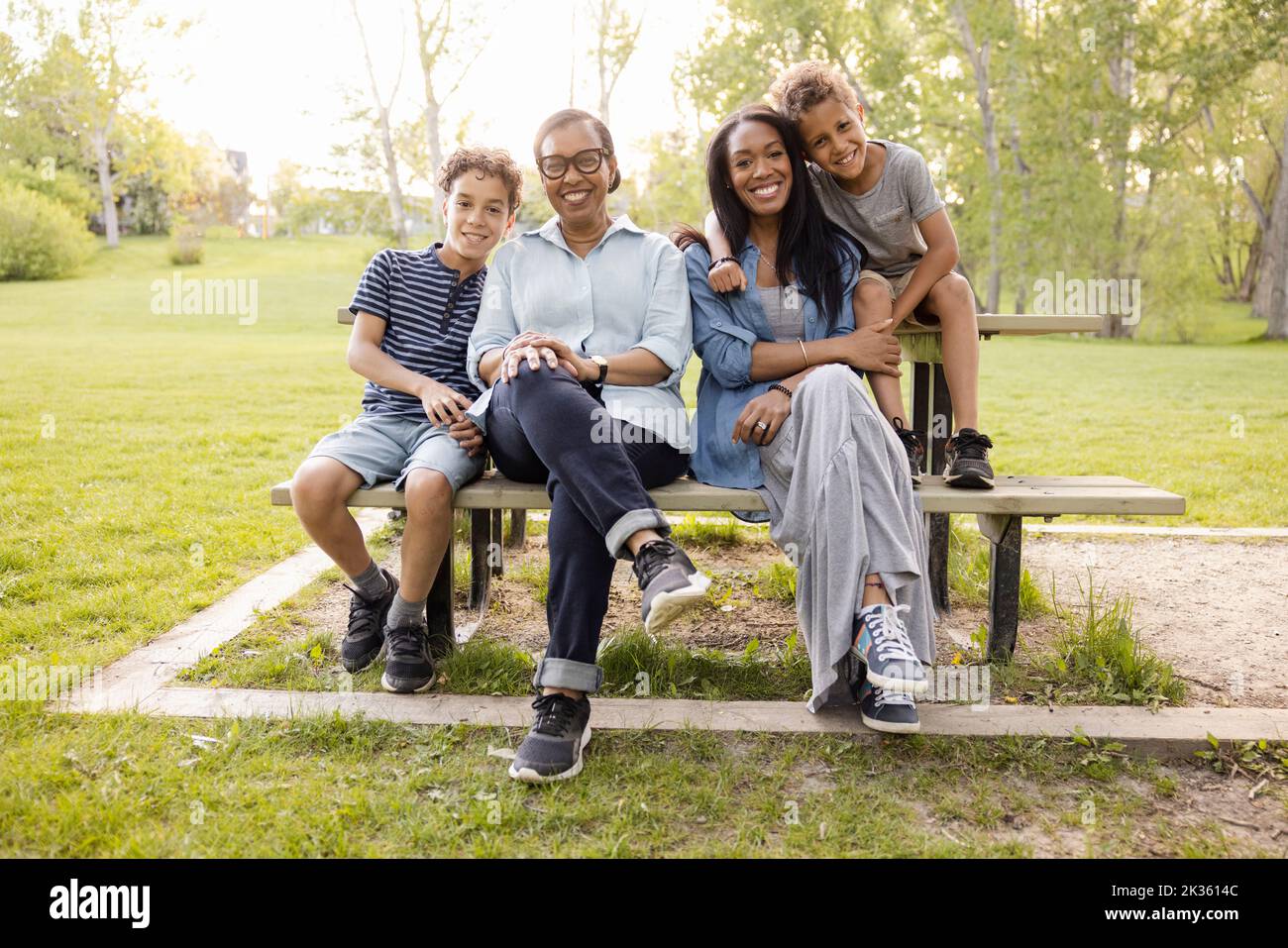 Portrait of affectionate family sitting on park bench Stock Photo - Alamy