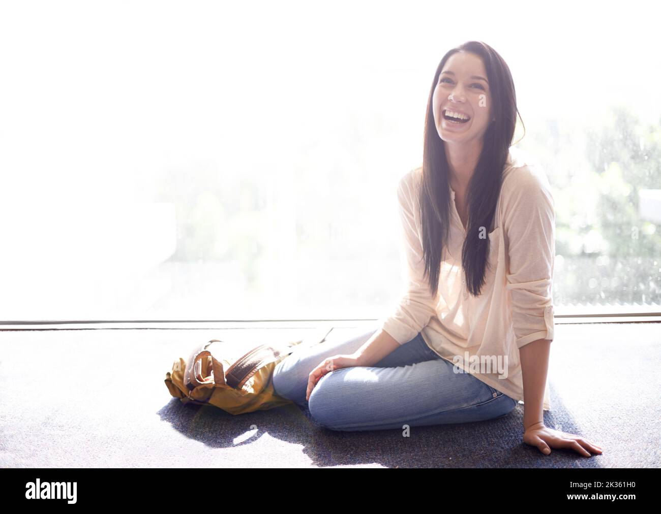 Beautiful laughter. a beautiful young woman laughing while sitting on ...
