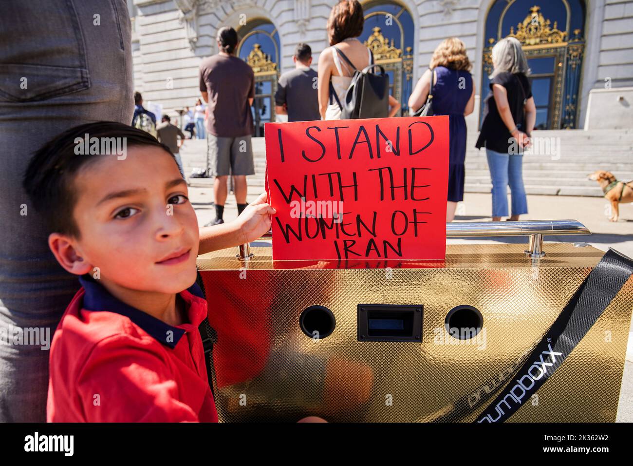 A child holds a placard that says "I stand with the women of Iran ...