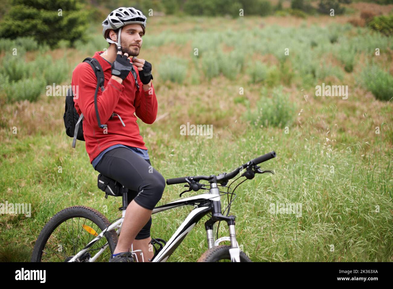 Preparing for the ride of his life. A young cyclist fastening his ...