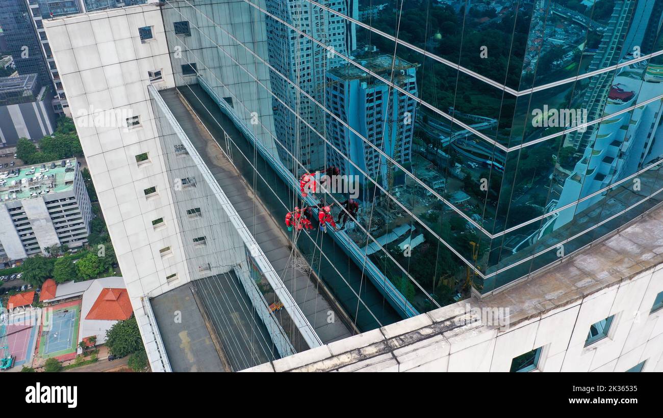 Window cleaning workers hanging outside blue glass office building ...