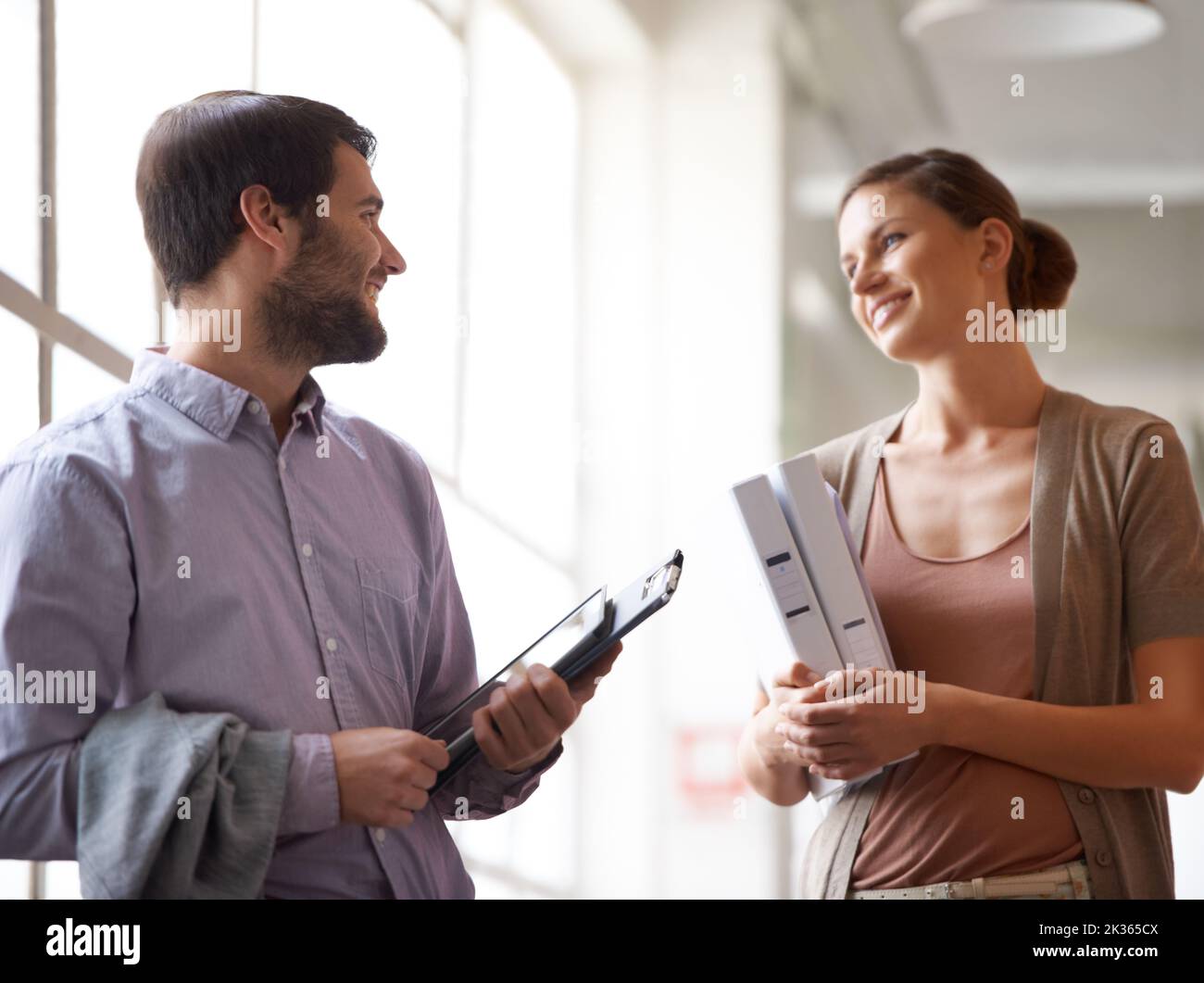 Catching up before a meeting. a coworkers talking to each other in a ...