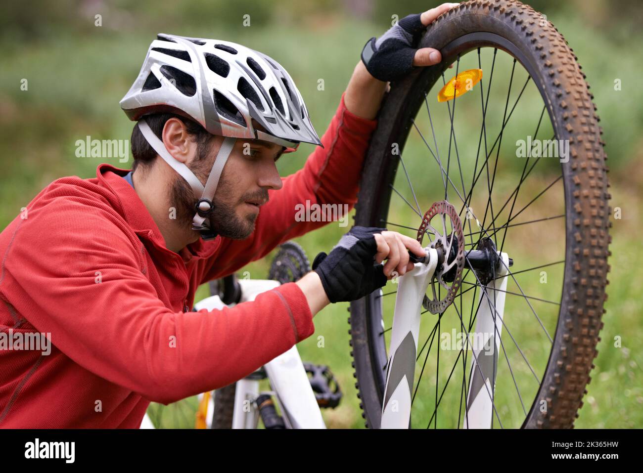 Tightening the screws for a better ride. A young man fixing the wheel ...