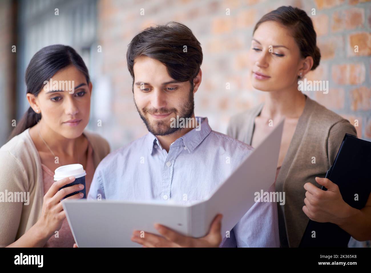 Working through their work files. three young colleagues in their ...