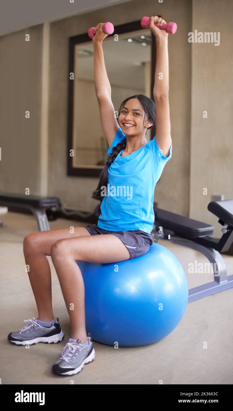 Light weight training to stay toned. A teenage girl lifting dumbbels ...