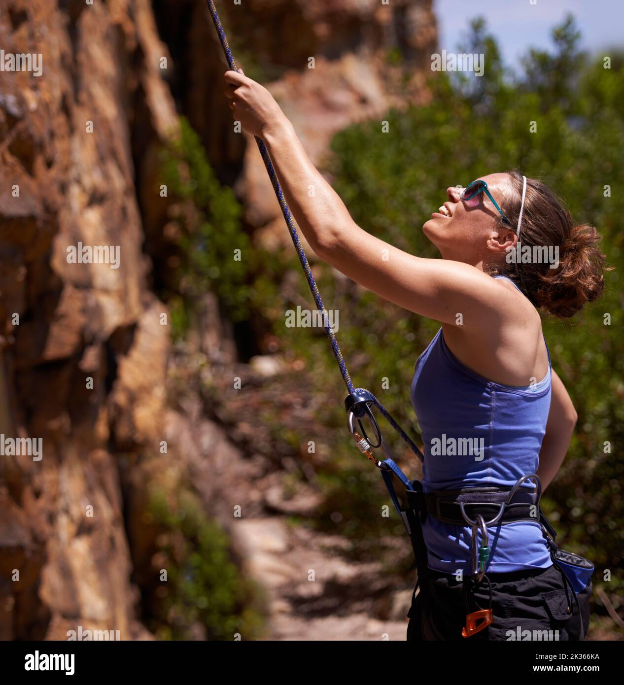 Ready to conquer this cliff. a young woman getting ready to climb up a ...