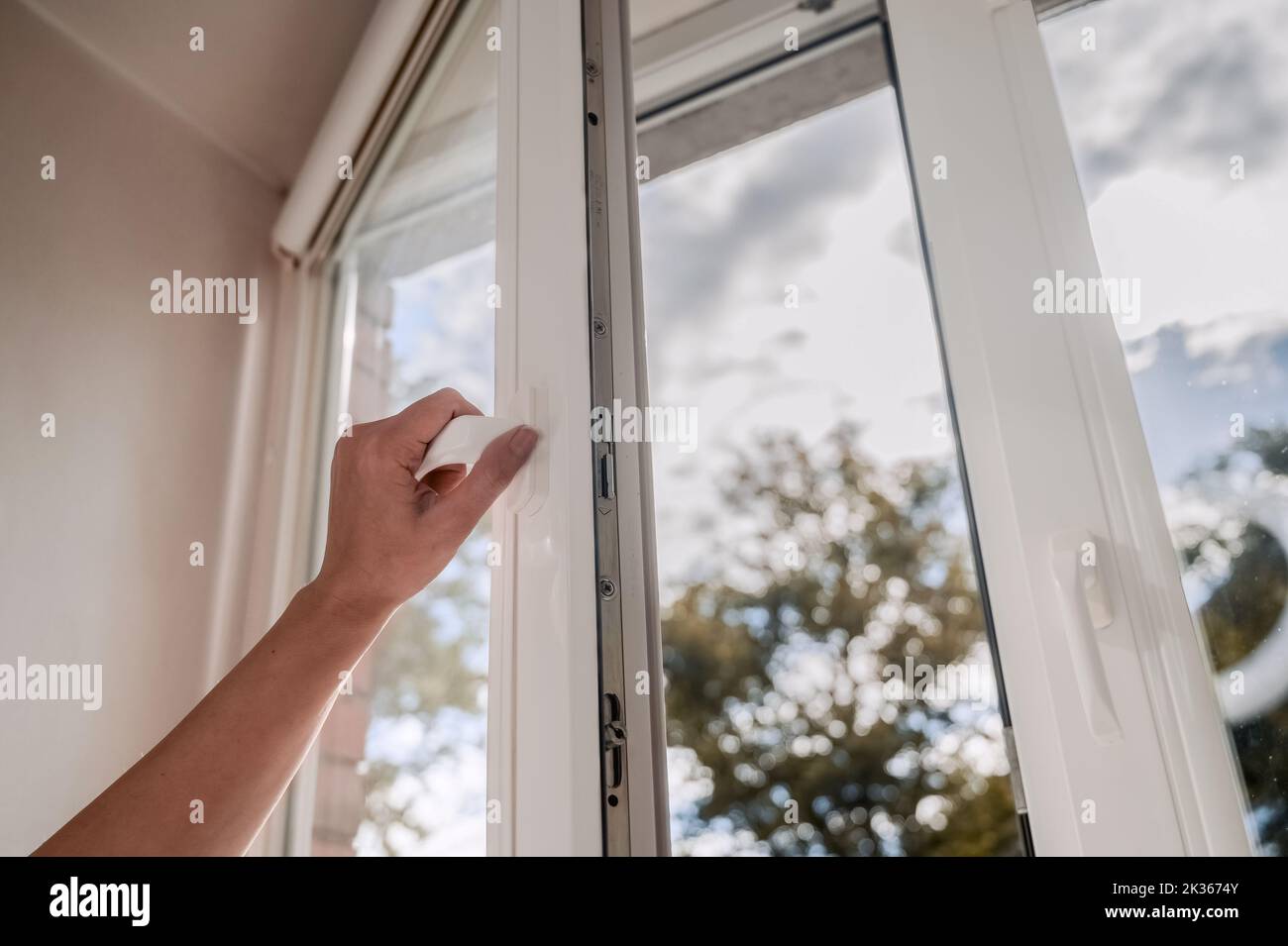 One sided open window. A hand opens a vinyl plastic window on a blue ...