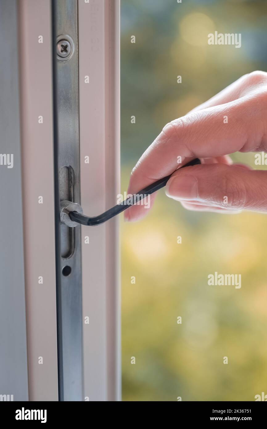 adjusting the white plastic window. a worker uses a hexagon to repair a ...