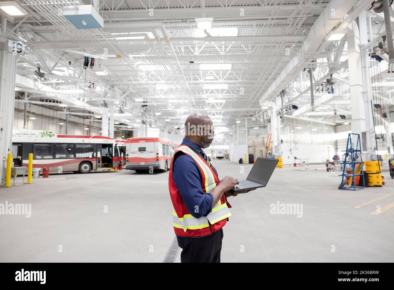 Male supervisor using laptop in maintenance facility Stock Photo - Alamy