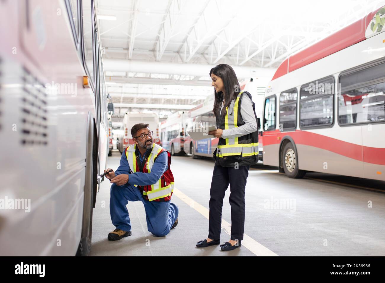 Engineers inspecting bus tire in maintenance facility Stock Photo - Alamy