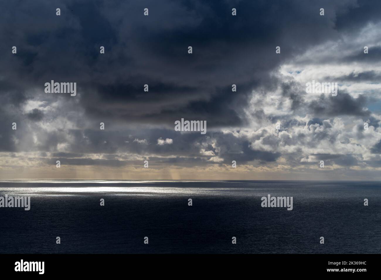 sun breaking through dark clouds over the Atlantic Ocean seen from the ...