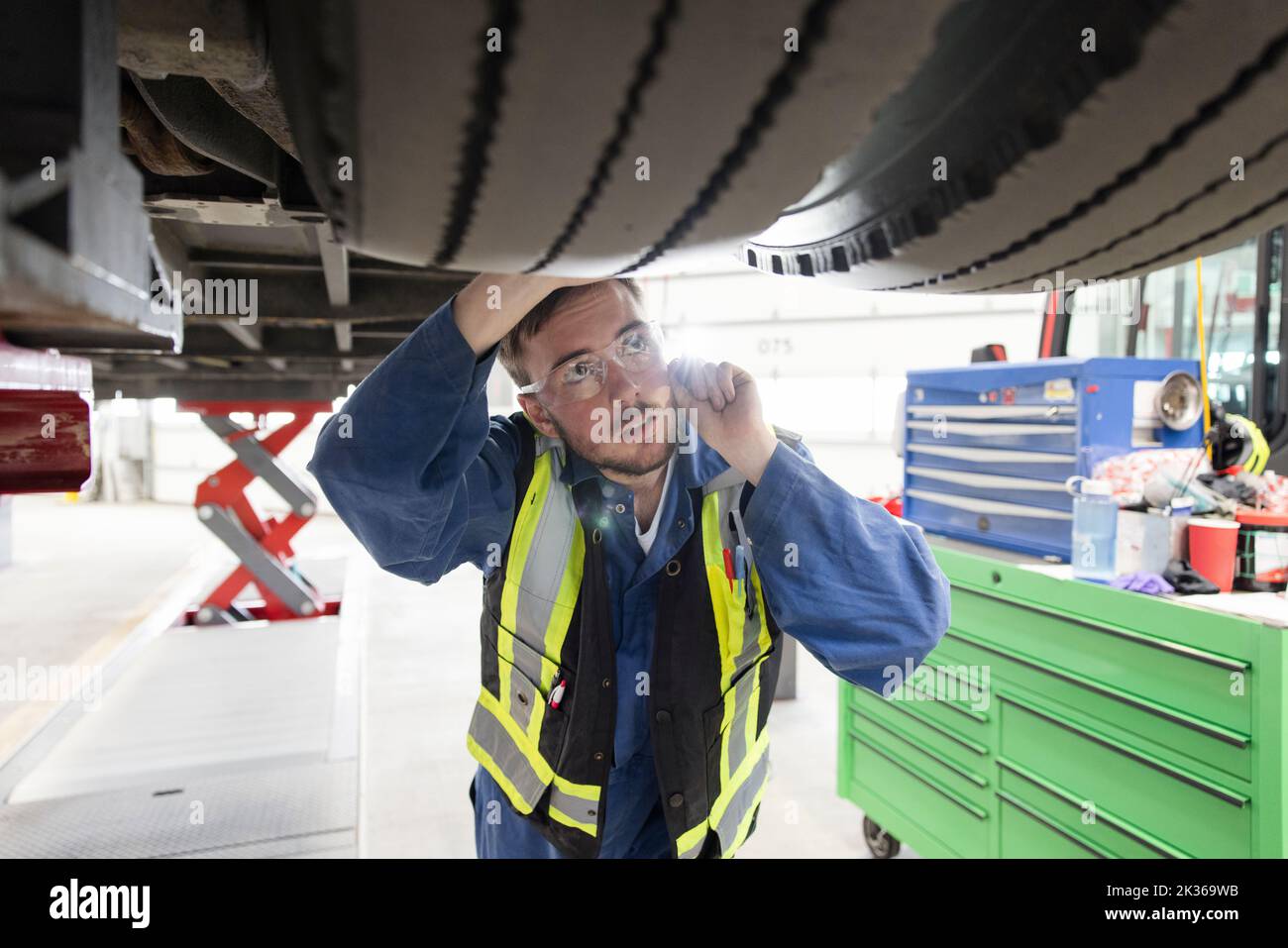Male mechanic with flashlight under bus in maintenance facility Stock ...