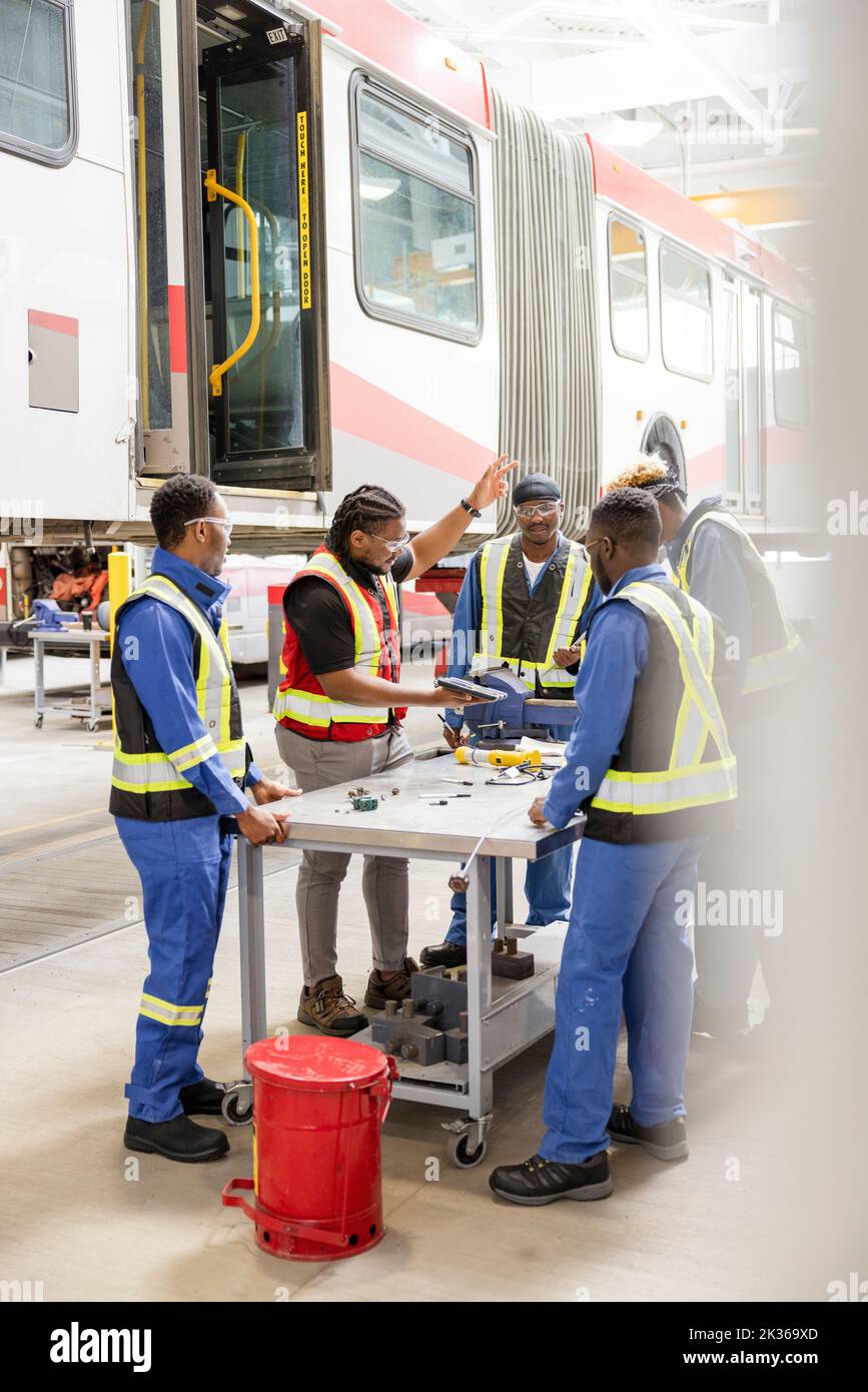 Engineers and mechanics meeting in bus maintenance facility Stock Photo ...