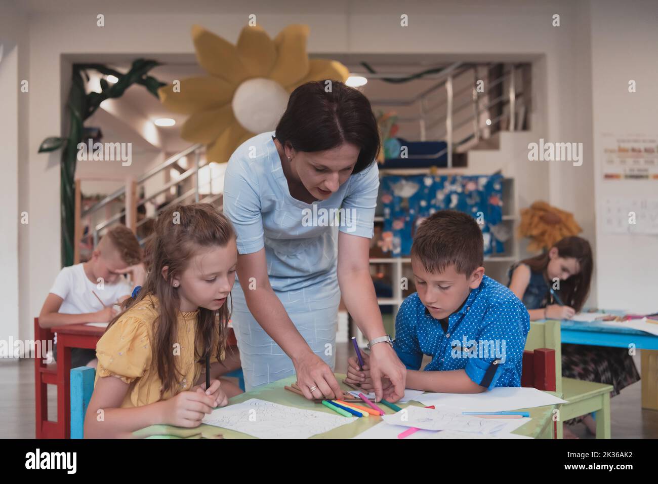 Creative kids during an art class in a daycare center or elementary school classroom drawing ...