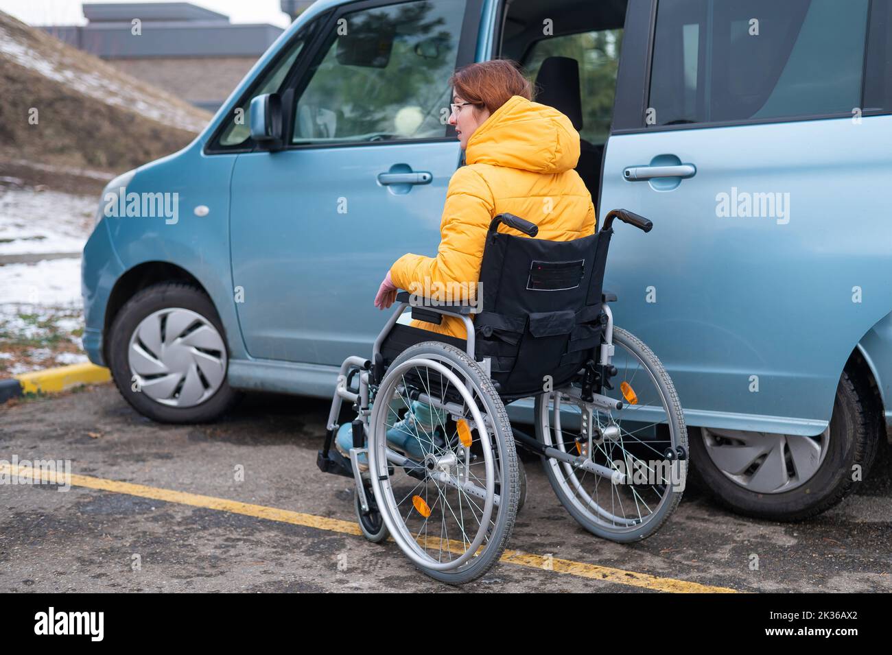 Caucasian woman in a wheelchair gets into the car Stock Photo - Alamy