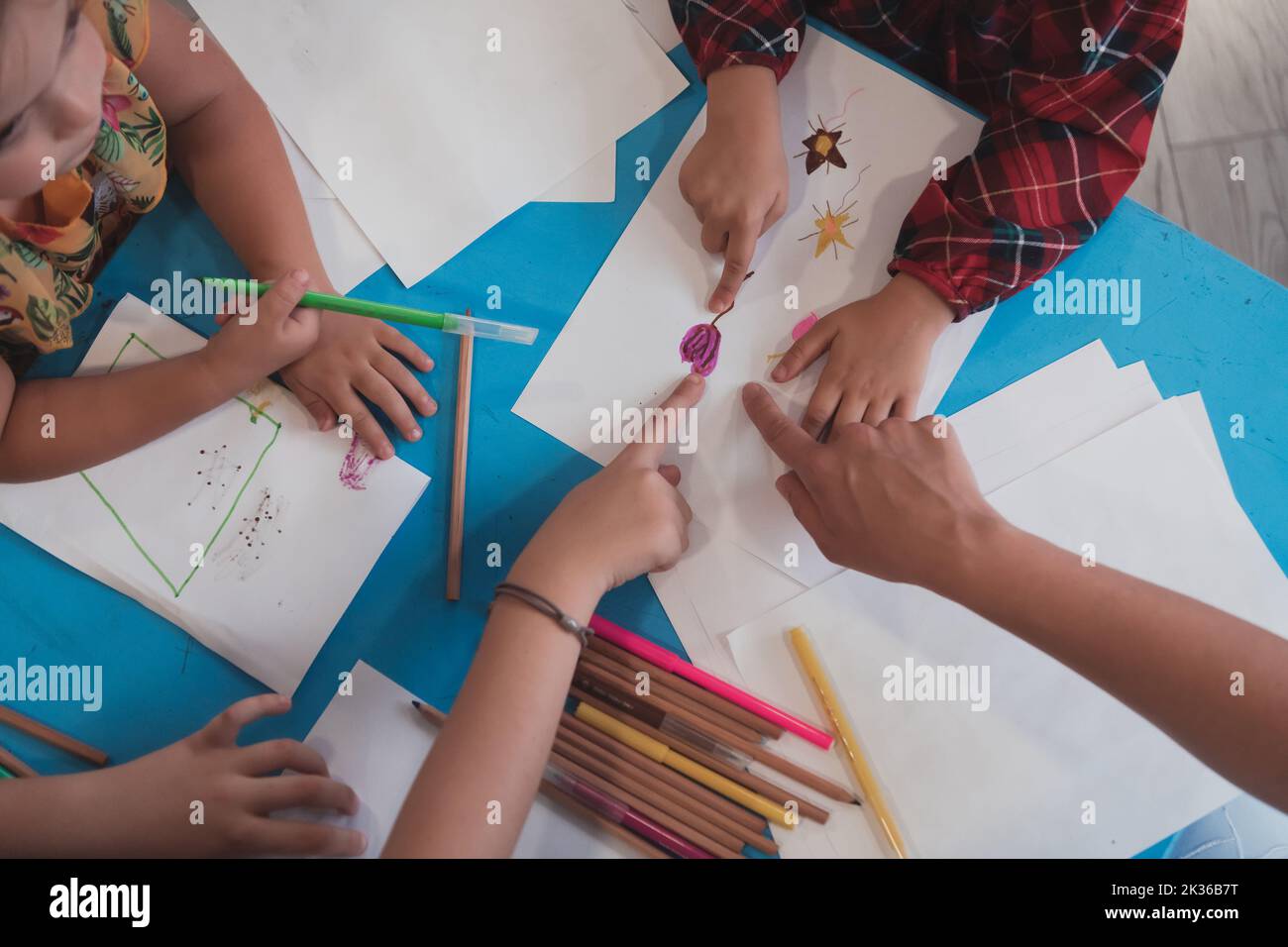 Creative kids during an art class in a daycare center or elementary school classroom drawing ...