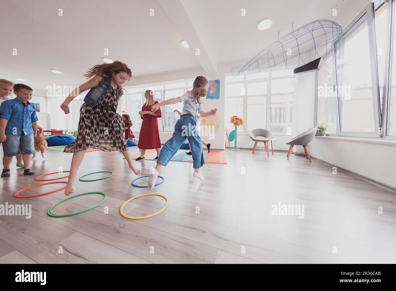 Small nursery school children with female teacher on floor indoors in ...