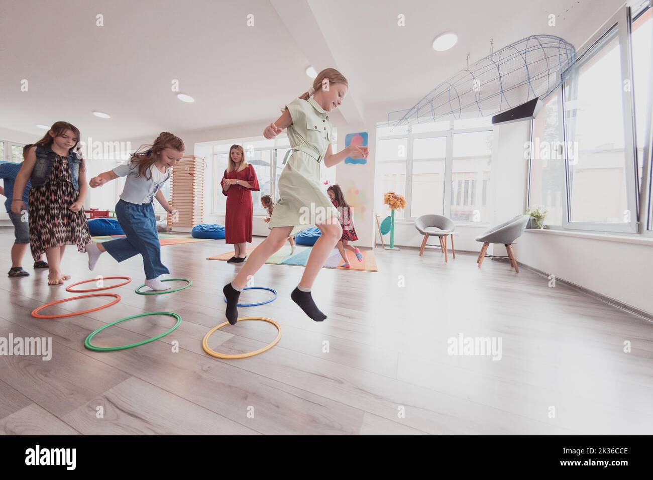 Small nursery school children with female teacher on floor indoors in ...
