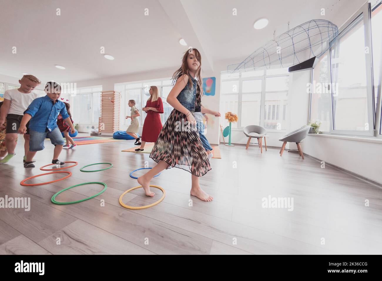 Small nursery school children with female teacher on floor indoors in ...